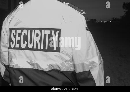 Grayscale shot of a security guard patrolling busy street and city at ...