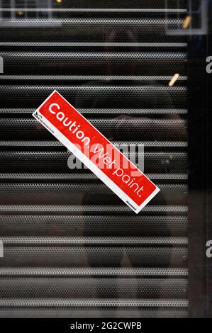 Caution Wet Paint sign on yellow tape cordoning off a small area by ...