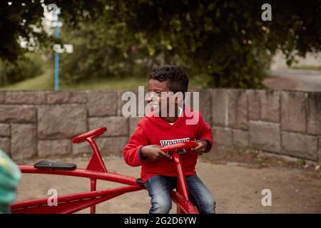 Boy spinning on the merry go round carousel at public playground ...