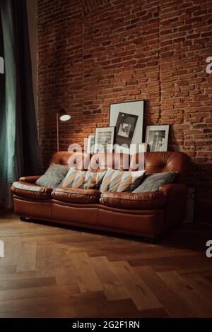 Vertical shot of a brown sofa with patterned pillows and pictures on ...