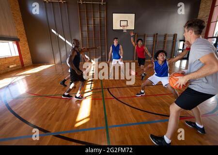 Diverse male basketball team and coach helping other player Stock Photo ...