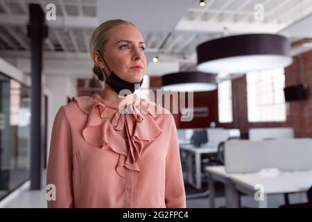thoughtful businesswoman in protective mask holding pen and notebook in ...