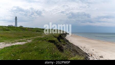 A panorama of the lighthouse and grassy sand dunes above the white sand ...