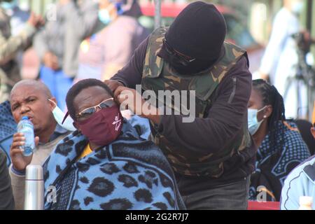 A bodyguard fixes Basotho Action Party leader Nqosa Mahao's face mask ...