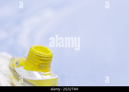 tube of watercolor yellow paint against the background of blue painted ...