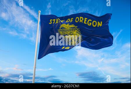flag of Oregon at cloudy sky background on sunset. Patriotic concept ...