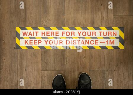 Wait your turn, keep your distance sign on a store floor Stock Photo ...