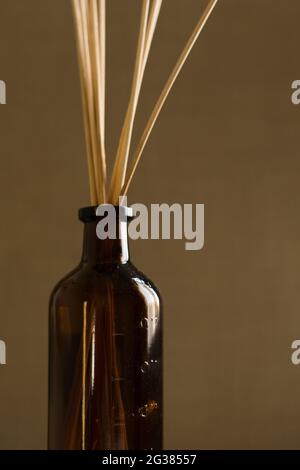 Dark glass diffuser bottle with natural reed sticks and a brown wood ...