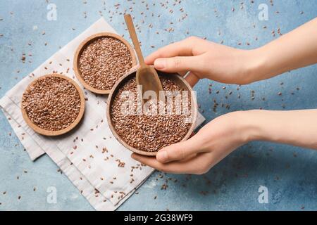 Female hands with bowl of flax seed on color wooden background Stock ...