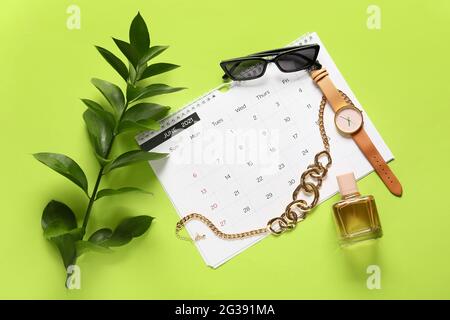 Calendar with female accessories on color wooden background ...