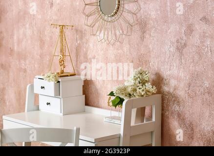 Modern workplace with vase and lilac flowers near color wall Stock ...
