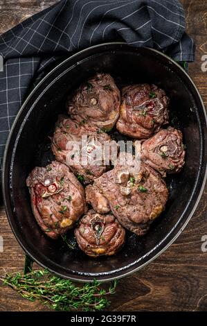 Stewed lamb neck meat in a pan with herbs. wooden background. Top view ...