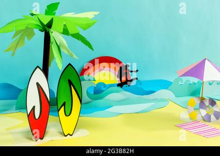 Creative papercraft of a beach, surfboards and a surfer silhouette on ...