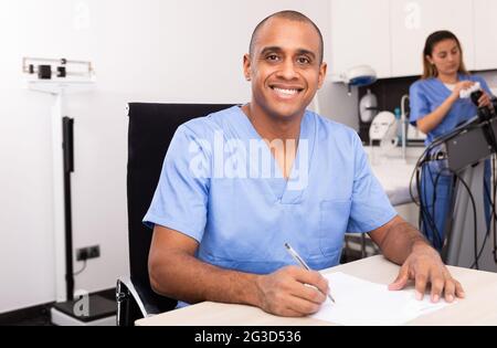 Male cosmetologist working with documents in aesthetic medicine office ...