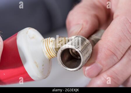 Plumber putting sealing paste on a thread, closeup Stock Photo - Alamy