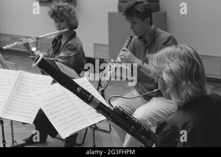 Seated musicians play bladder instruments in a room with showcases ...