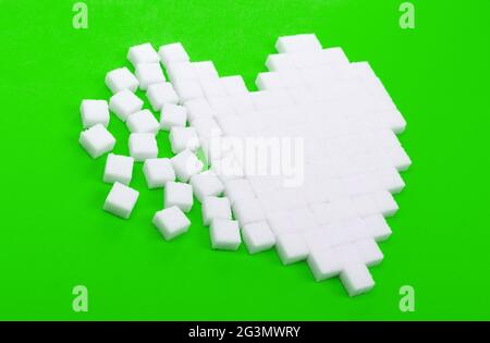 A broken heart made of sugar cubes lies on a trendy pastel lime ...