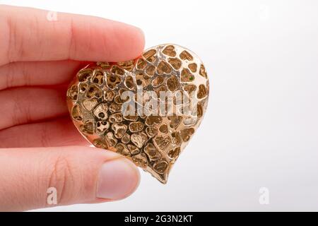 Heart shaped gold color metal object in hand Stock Photo - Alamy