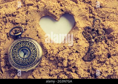 Retro style watch beside a heart shape made on sand Stock Photo - Alamy