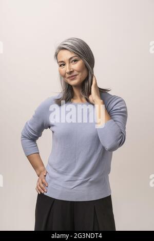 Smiling Asian woman touches her grey hair Stock Photo - Alamy