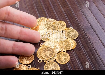 Plenty of fake gold coins in hand on wooden background Stock Photo - Alamy
