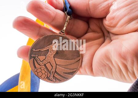 Hand holding a medal with blue and yellow ribbon Stock Photo - Alamy