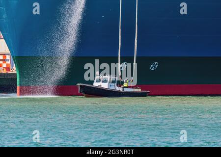 A port services vessel takes lines from a container ship as it berths ...