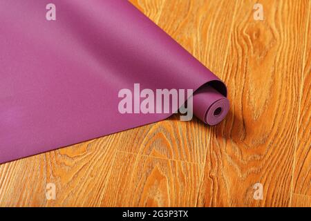 An unfolded lilac-colored yoga mat is unfolded on the wooden floor. Top ...