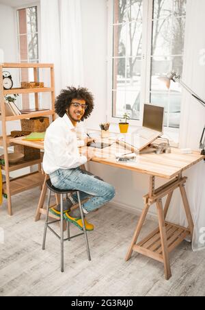 young copywriter looking at laptop near digital tablet and notebook on ...