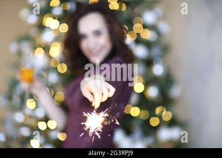 Happy woman with sparkler and champagne against Christmas tree Stock ...