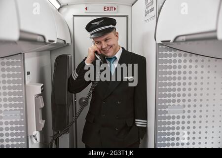 Male pilot talk on board phone in airplane Stock Photo - Alamy