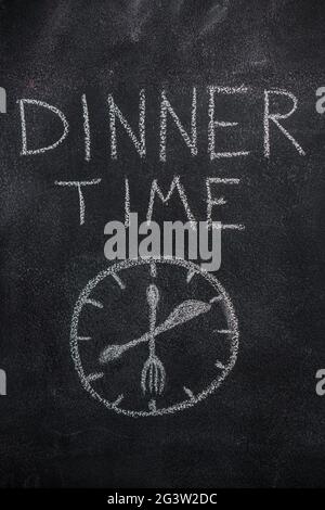 Dinner time text with clock on black chalkboard Stock Photo - Alamy