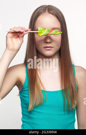 Sweet, shy girl closed her eyes with her hand. Isolated on blue ...