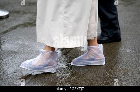 A racegoer wears rain covers on her feet as she arrives for day four of ...