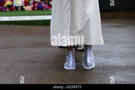 A racegoer wears rain covers on her feet as she arrives for day four of ...