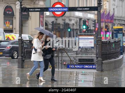 Friends share hand gel as they walk past the entrance to Piccadilly ...