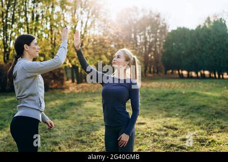 Two girls clapping hands, smiling, side view Stock Photo - Alamy