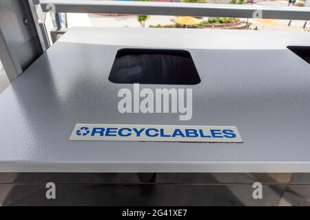 Angled view of a covered, grey and black outdoor trash bin labelled for ...