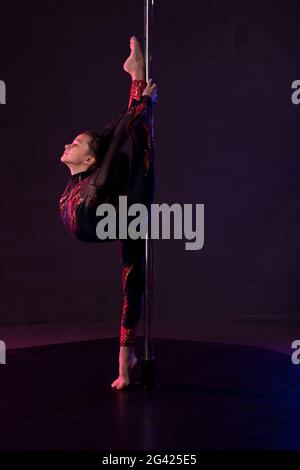 Vertical shot of female gymnast doing backbend exercise at aerial yoga ...