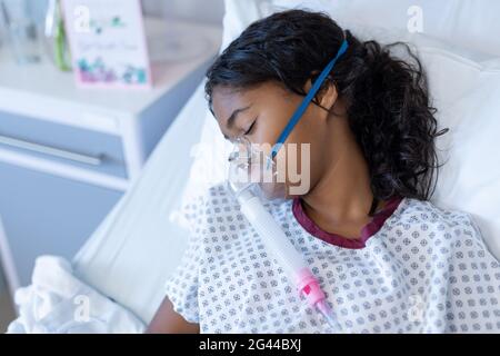 Sick mixed race girl asleep in hospital bed wearing oxygen mask ...