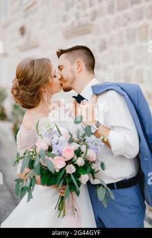 The bride and groom stand hugging at a brick wall in the old city and ...