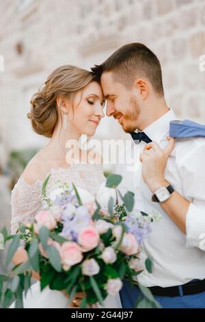 happy bride with closed eyes near elegant muslim groom isolated on grey ...