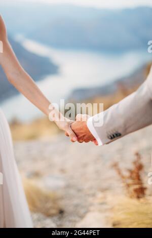 Bride and groom hold hands while standing on the road against the ...
