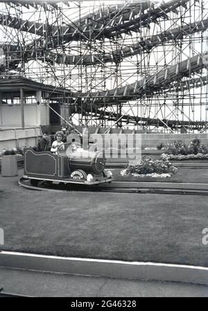 1960s, historical, outside at a funfair, a young women standing playing ...