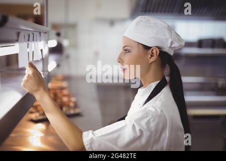 Female chef looking at order list in kitchen Stock Photo - Alamy