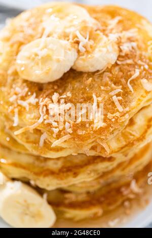 Stack of freshly baked coconut banana pancakes garnished with sliced ...