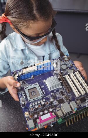 Focused elementary student examining circuit board on desk at ...