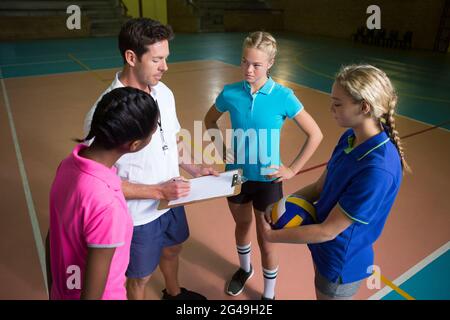 Smiling female coach talking with volleyball players at court Stock ...