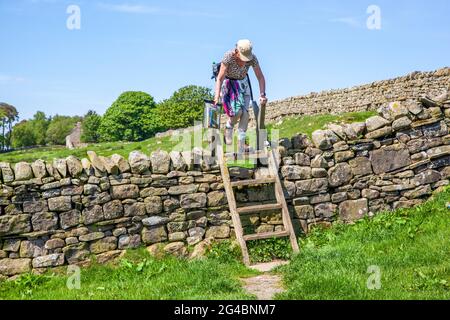 Woman climbing over over wall Stock Photo - Alamy
