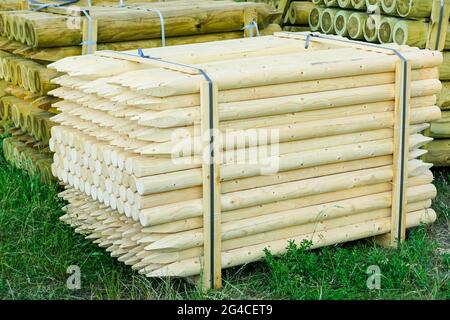 pallet with long round natural wooden fence posts with a sharpened tip ...